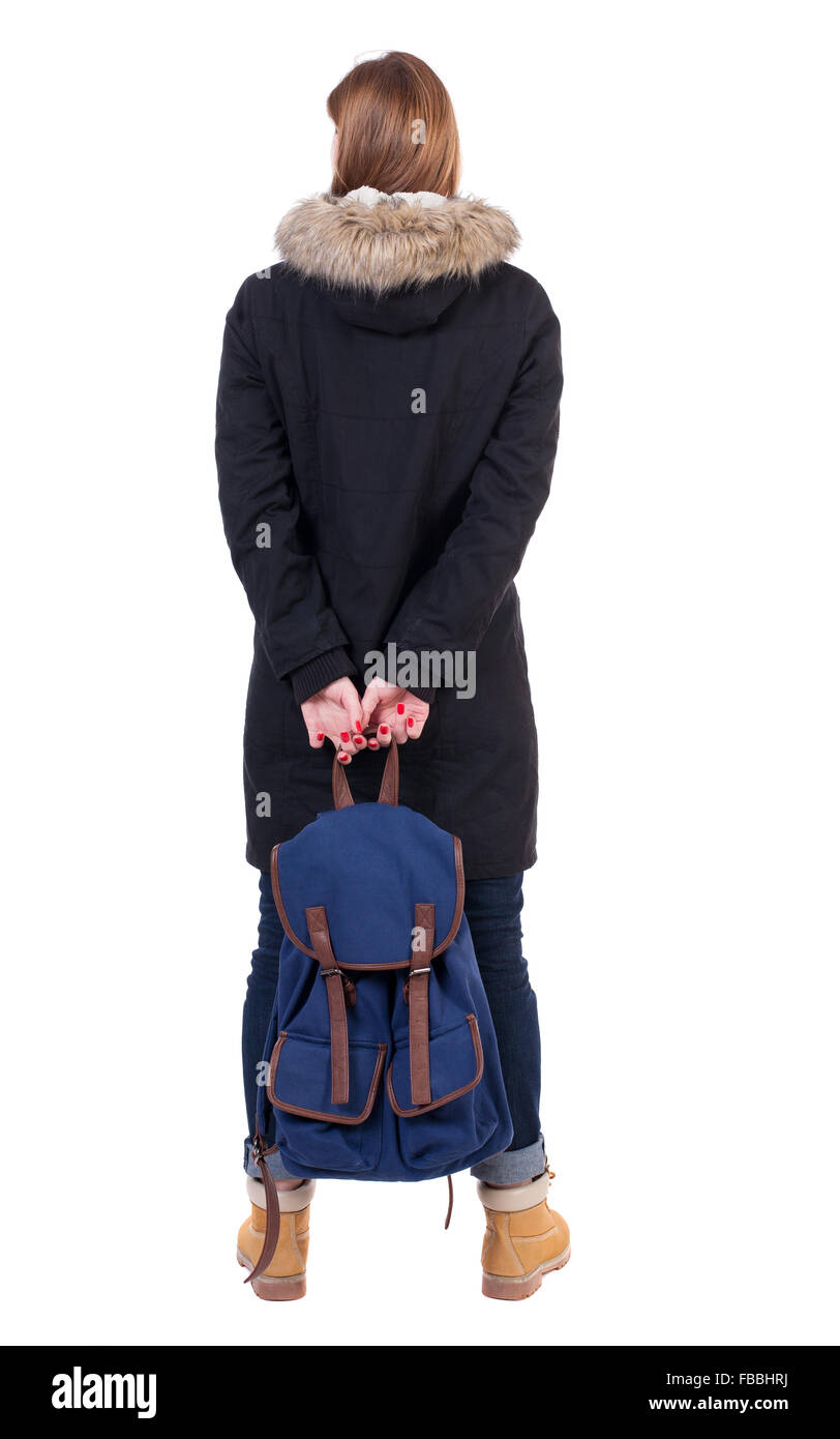 Back view woman in winter jacket with a backpack looking up. Standing ...