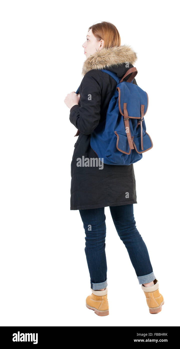 Back view woman in winter jacket with a backpack looking up. Standing ...