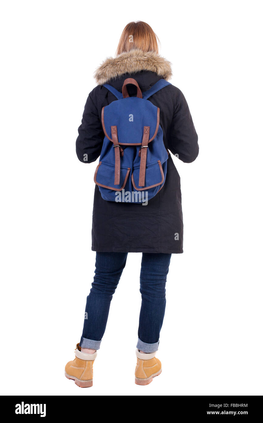 Back view woman in winter jacket with a backpack looking up. Standing ...