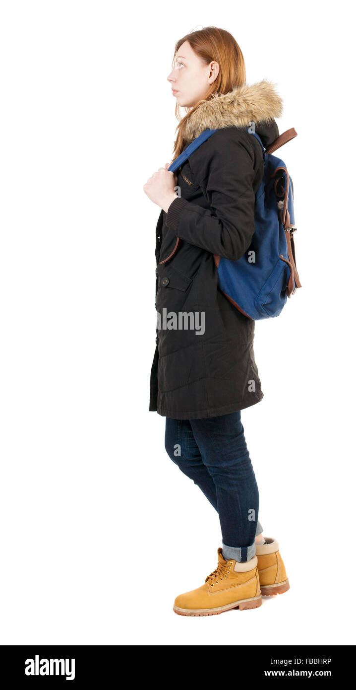 Back view woman in winter jacket with a backpack looking up. Standing ...