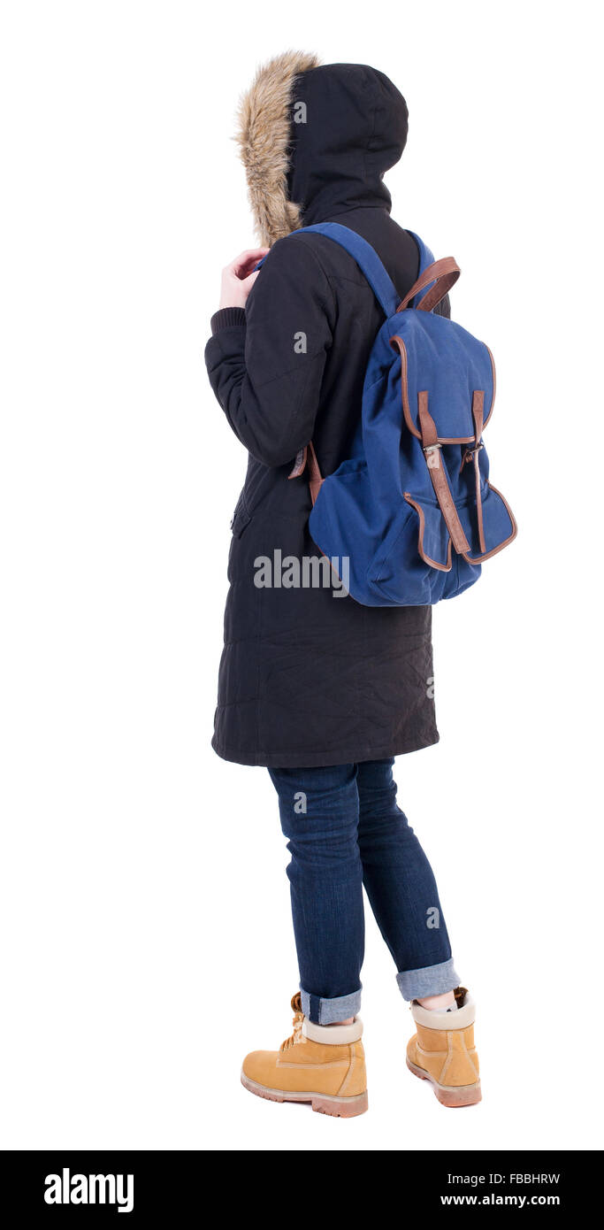 Back view woman in winter jacket with a backpack looking up. Standing ...