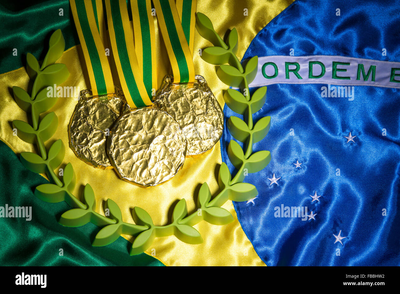 Gold medals surrounded by laurel wreath resting on shiny Brazil flag ...