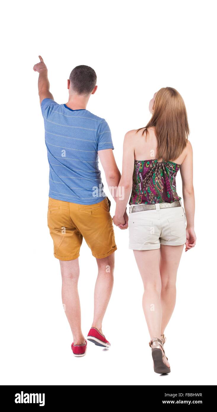 Back view of walking young couple (man and woman) pointing. going ...