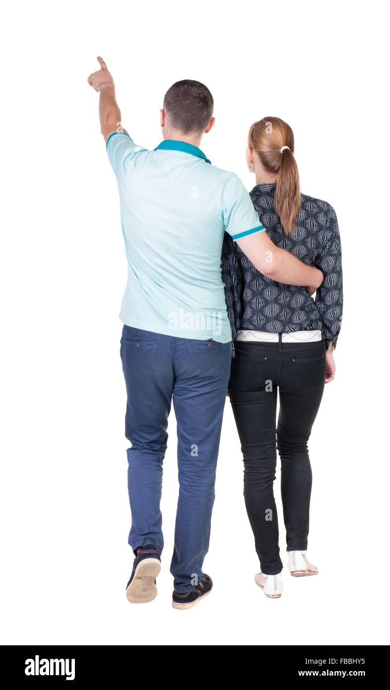 Back view of walking young couple (man and woman) pointing. Rear view ...
