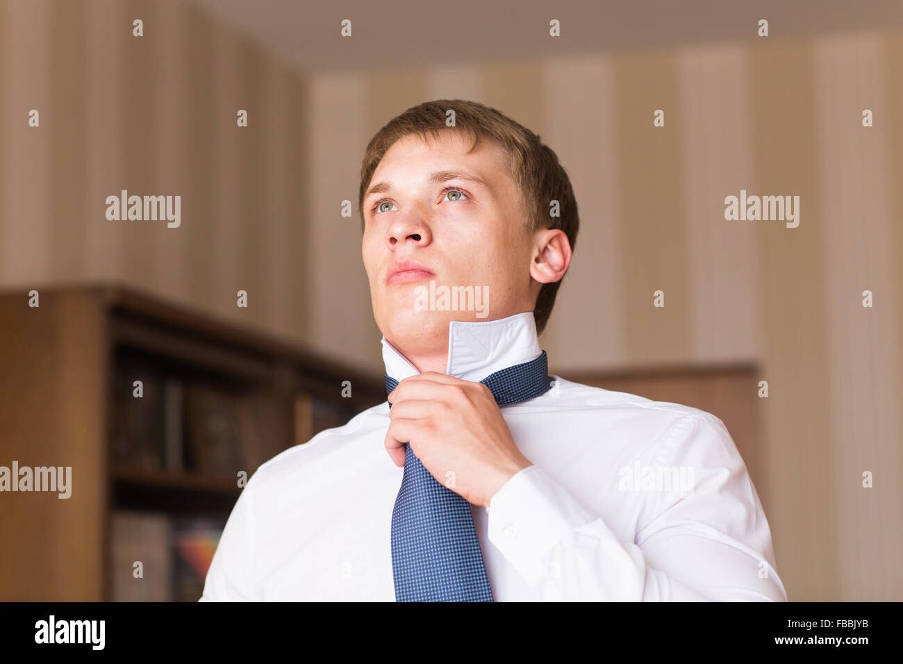 Portrait of a man adjusting his shirt and tie Stock Photo - Alamy