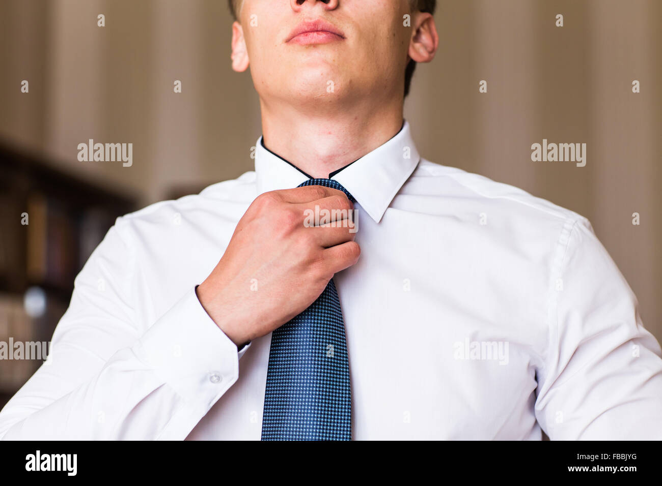 Portrait of a man adjusting his shirt and tie Stock Photo - Alamy