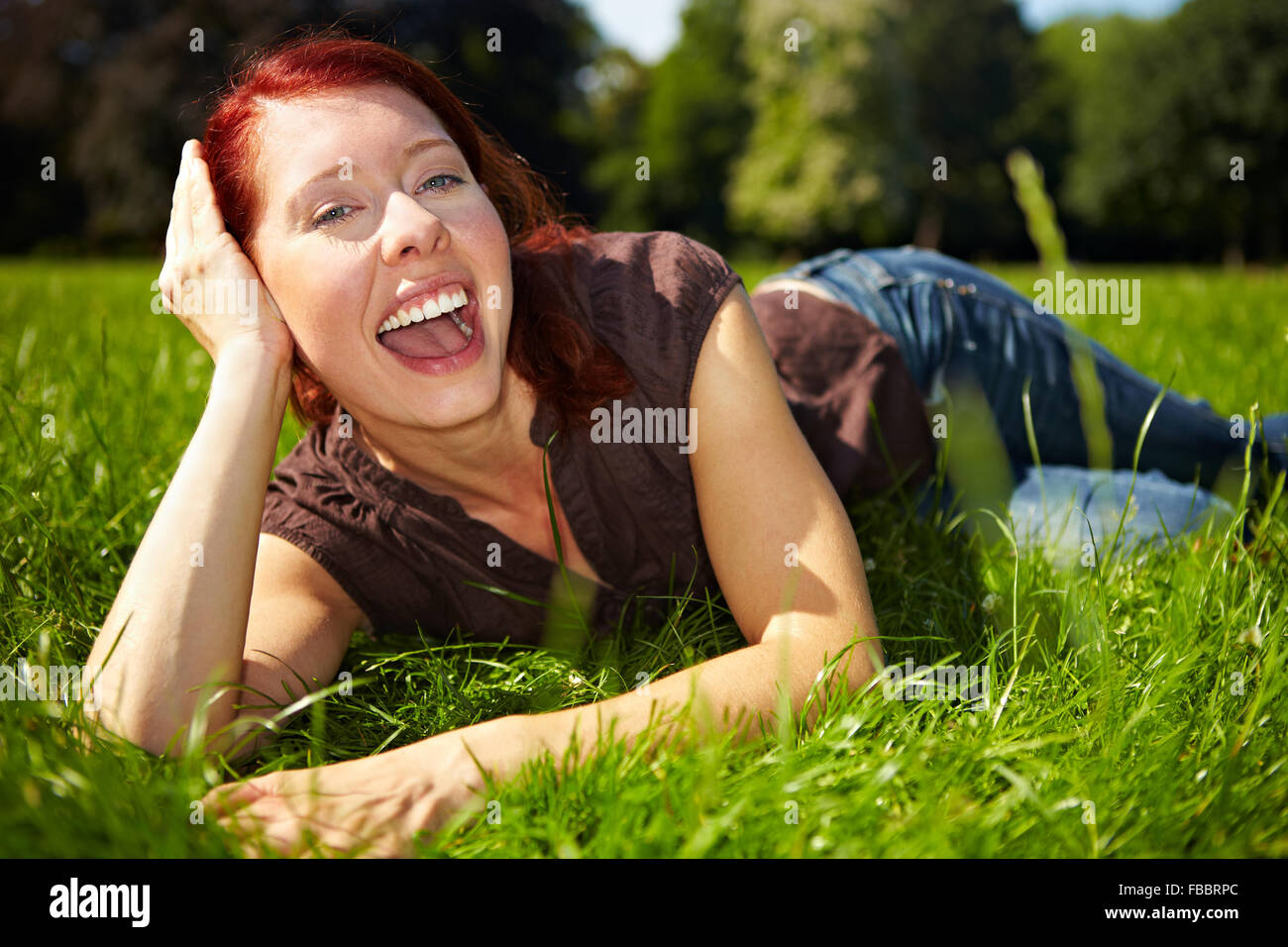 Young smiling happy woman laying outdoors in a park Stock Photo - Alamy