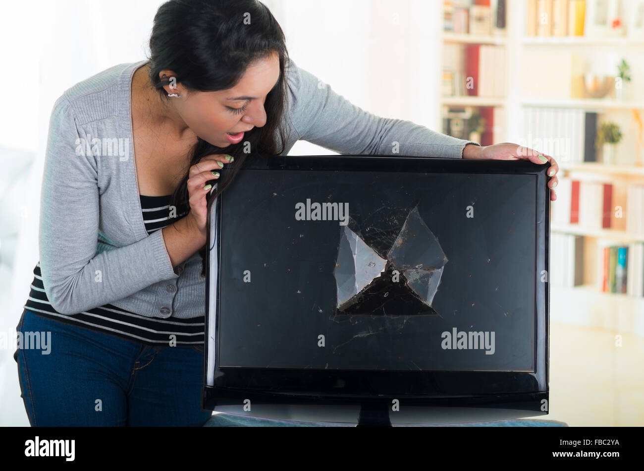 Brunette female looking over broken computer screen with shocked facial ...