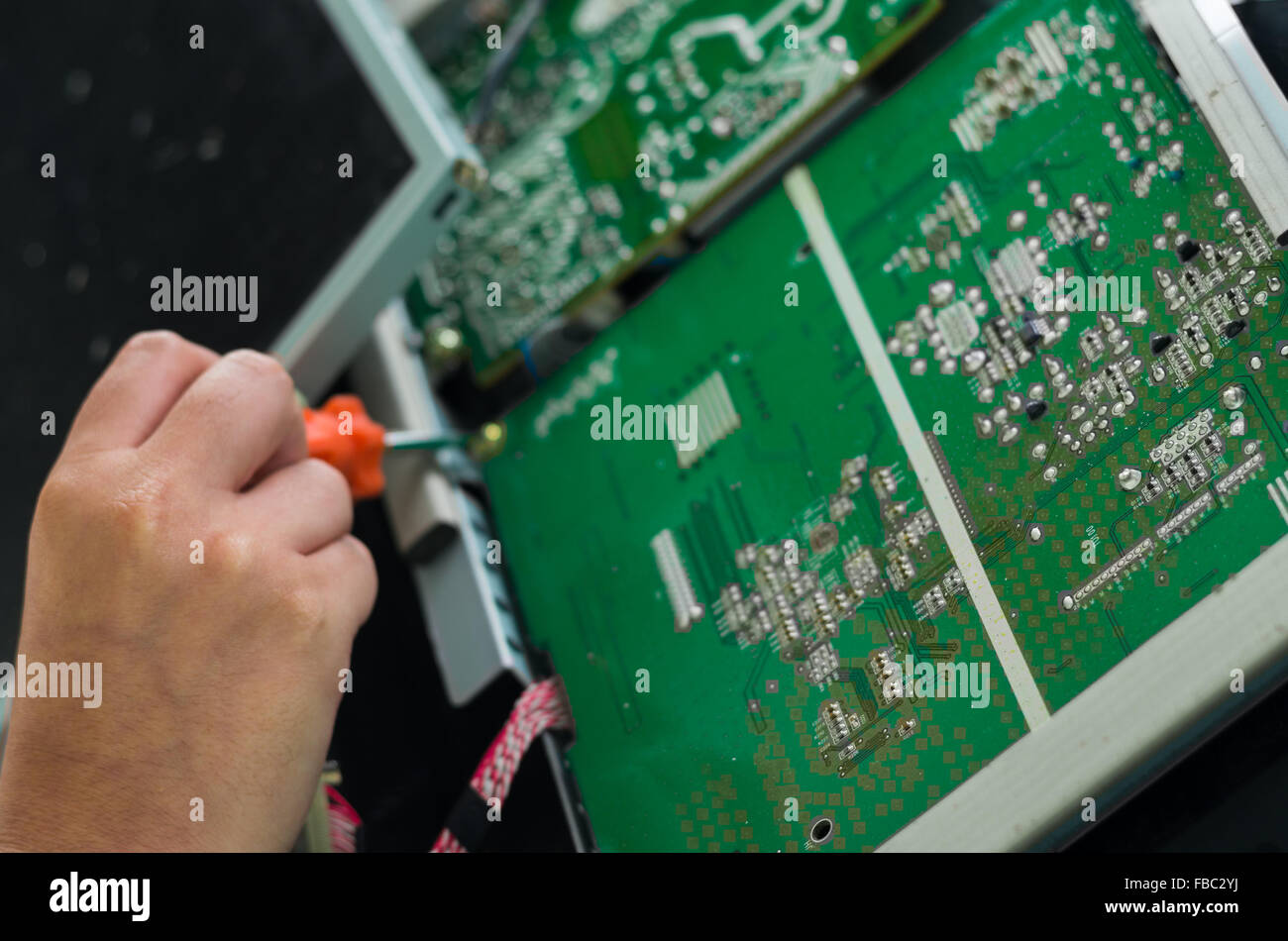 Hands working with electronic circuit board from broken computer screen ...