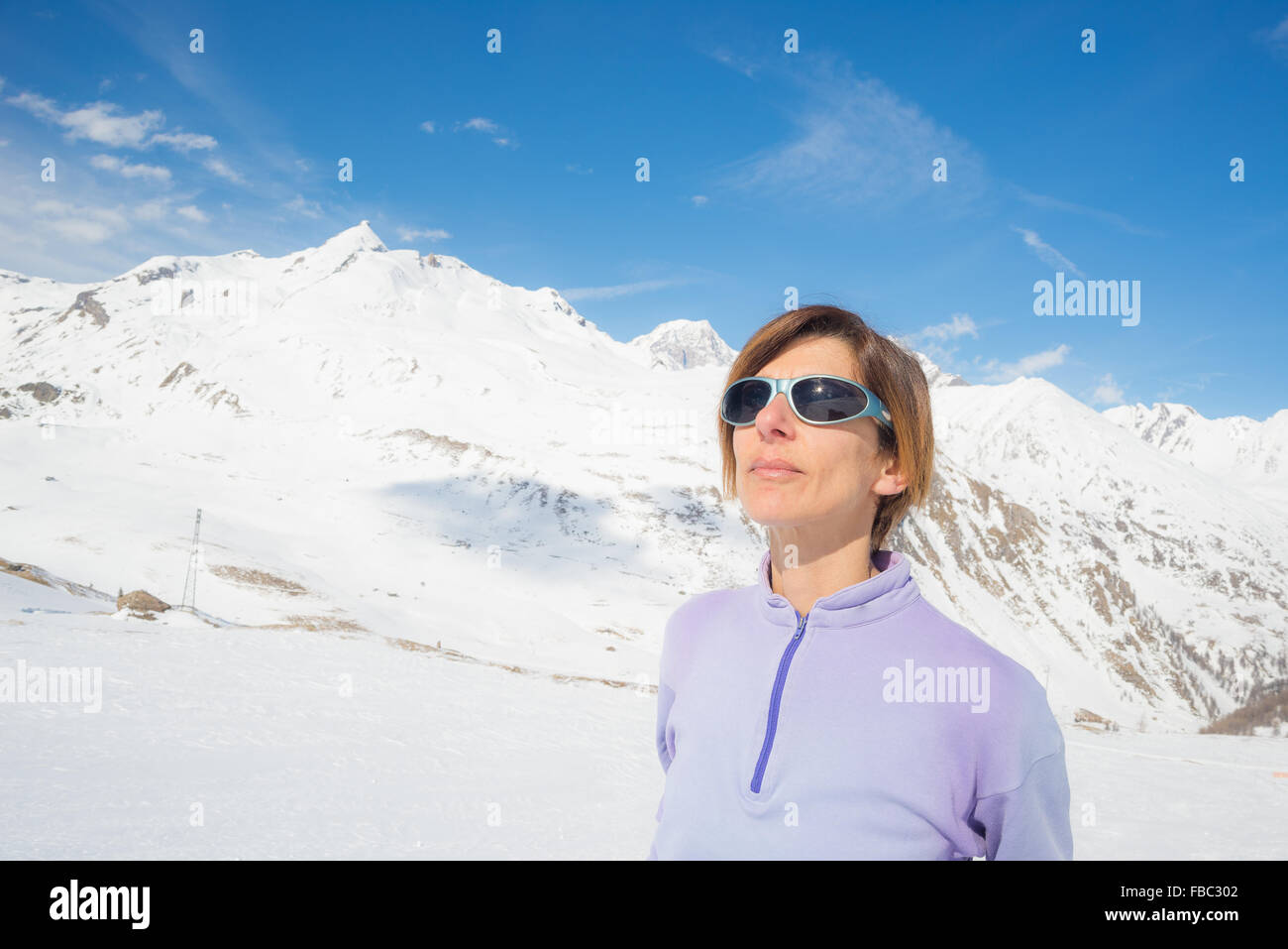 Adult female skier with backpack and sunglasses watching the sun in the ...