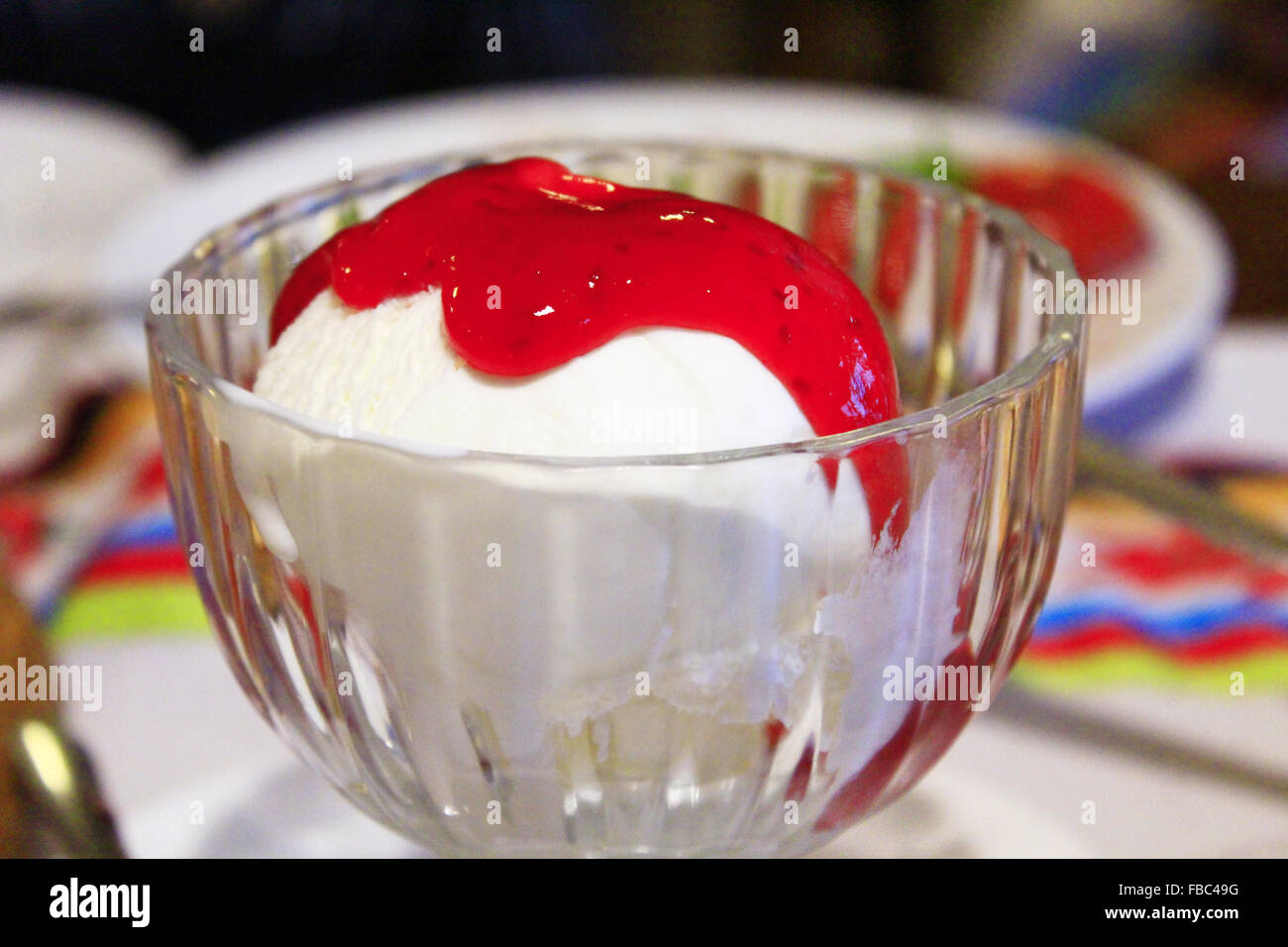 Ice cream poured red and sweet raspberry syrup Stock Photo - Alamy