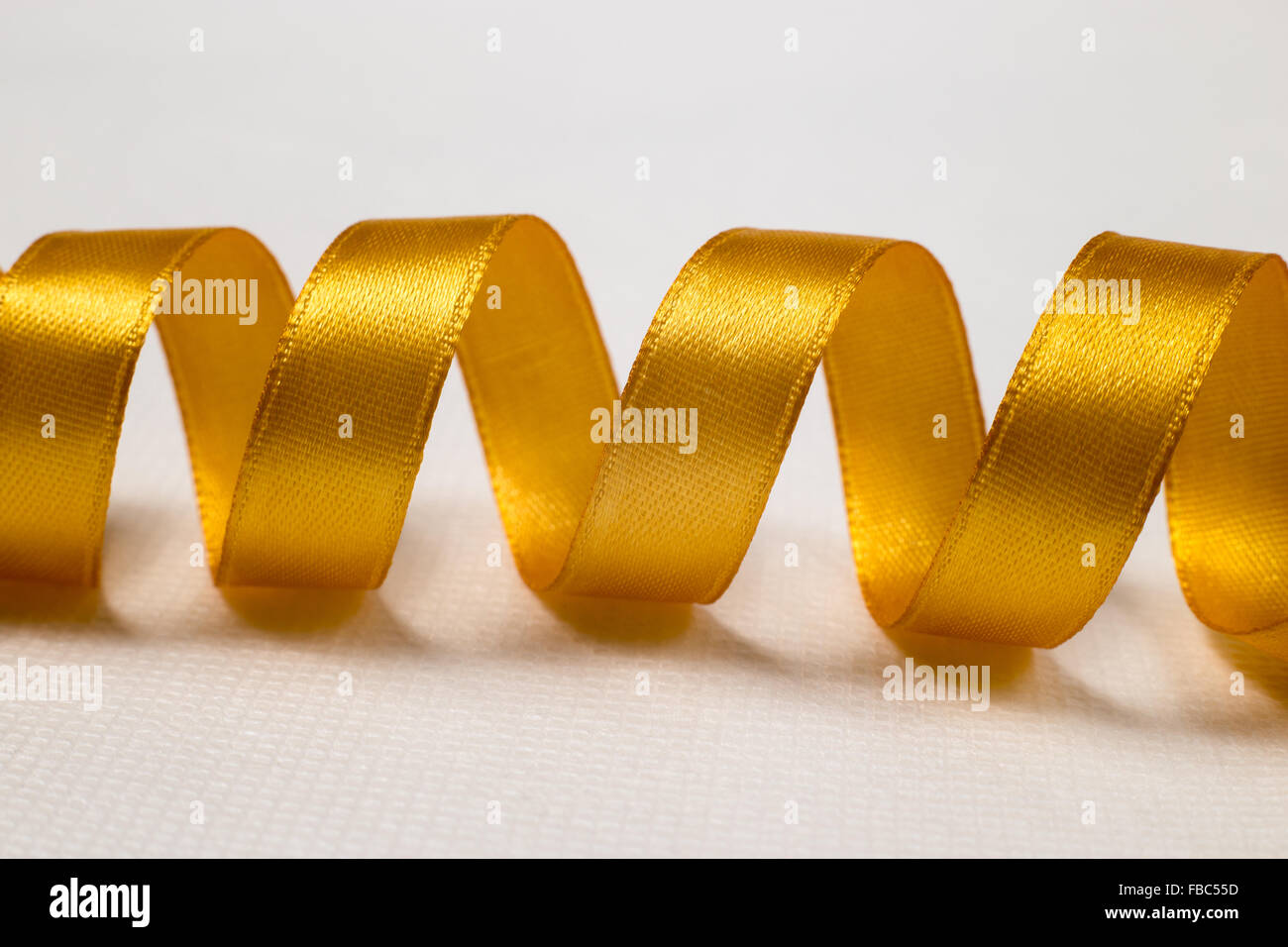 Close-up of perfectly straight curls of golden ribbon on white ...