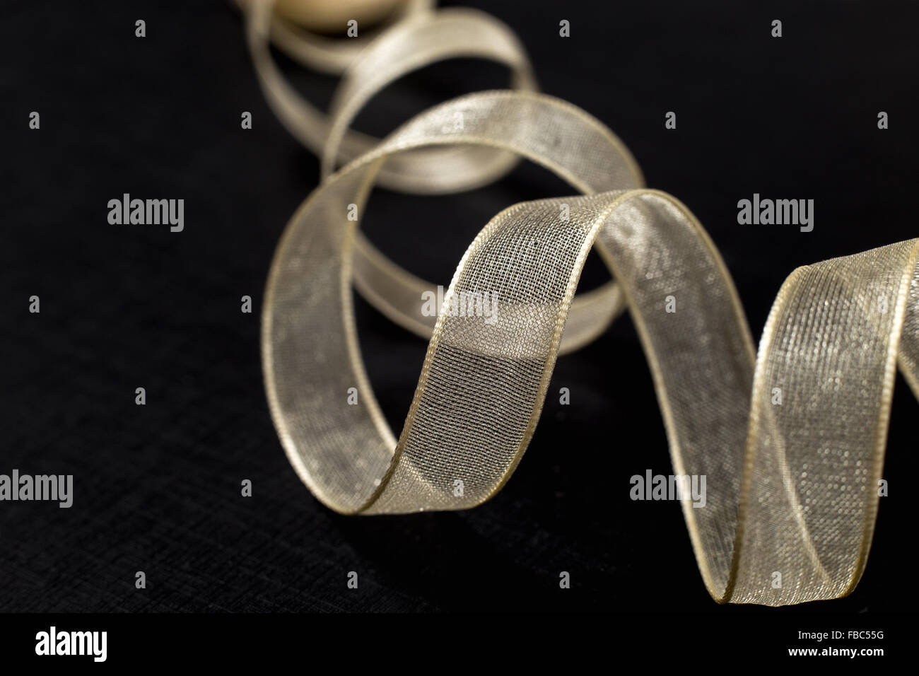 Close-up of white transparent ribbon curls in perspective on black ...