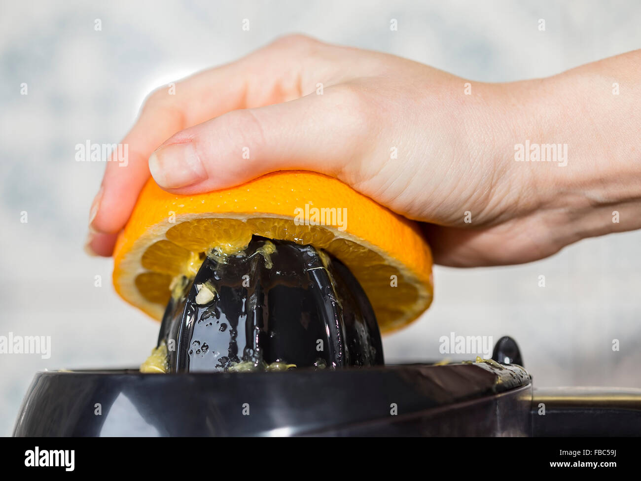 Squeezing orange to extract some healthy juice Stock Photo - Alamy