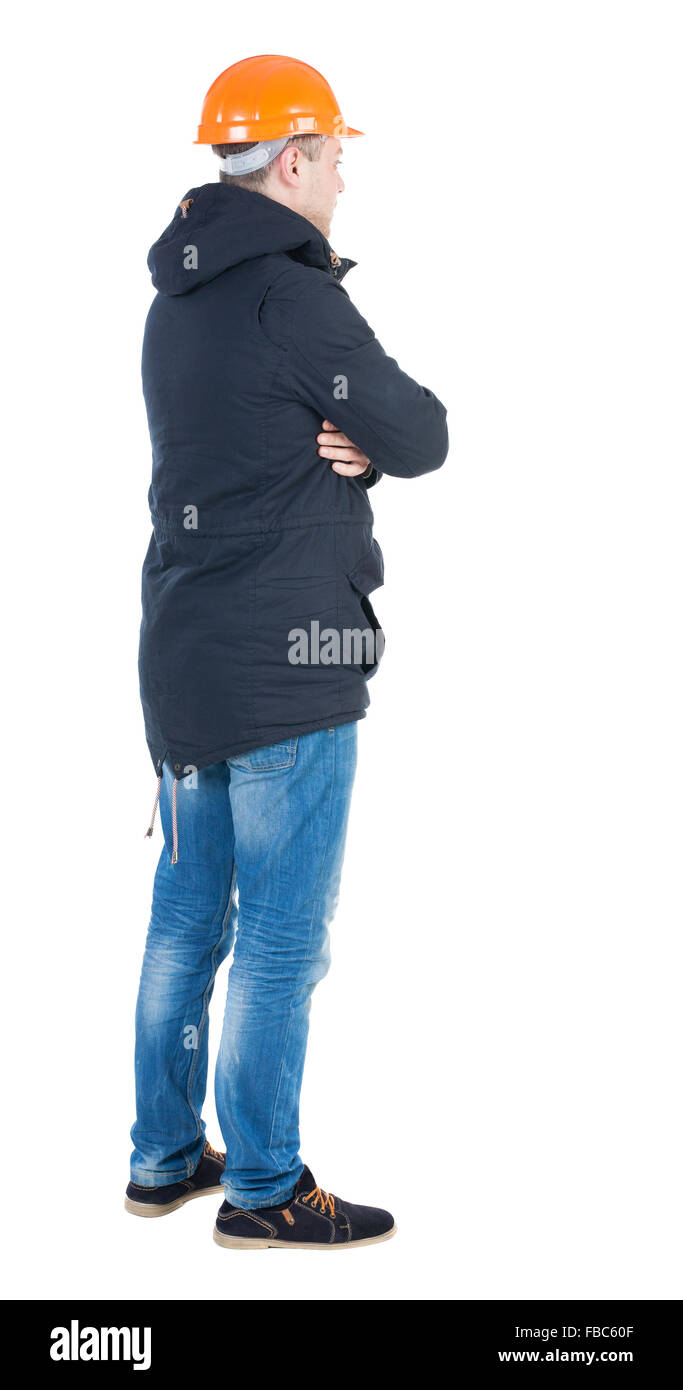Backview of an engineer in construction helmet stands and parka ...