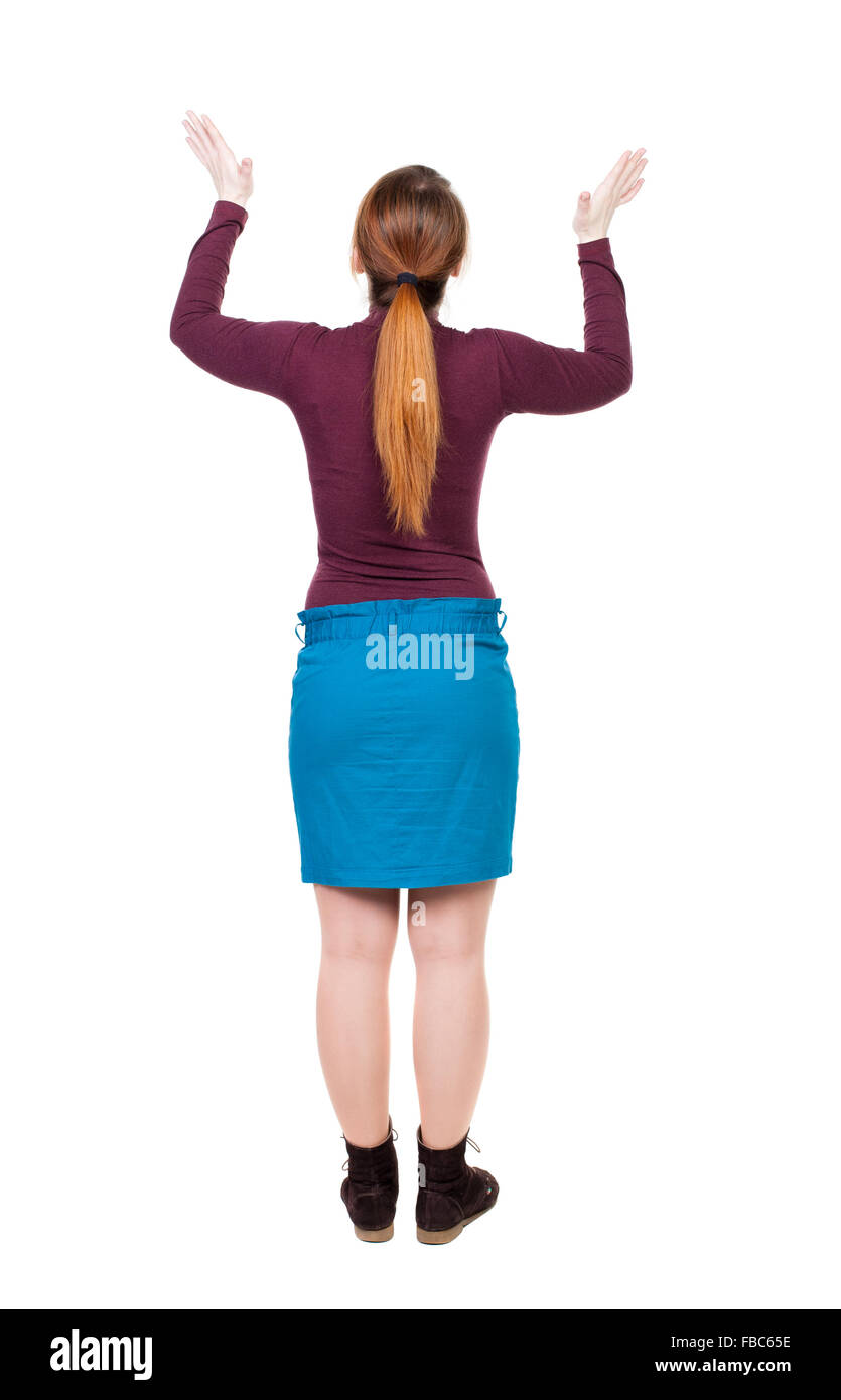 Back view of Beautiful woman in jeans looking at wall and Holds hand up ...