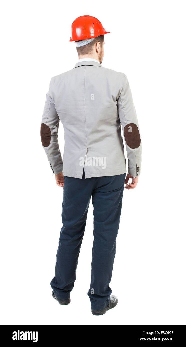 Backview of an engineer in construction helmet stands. Standing young ...