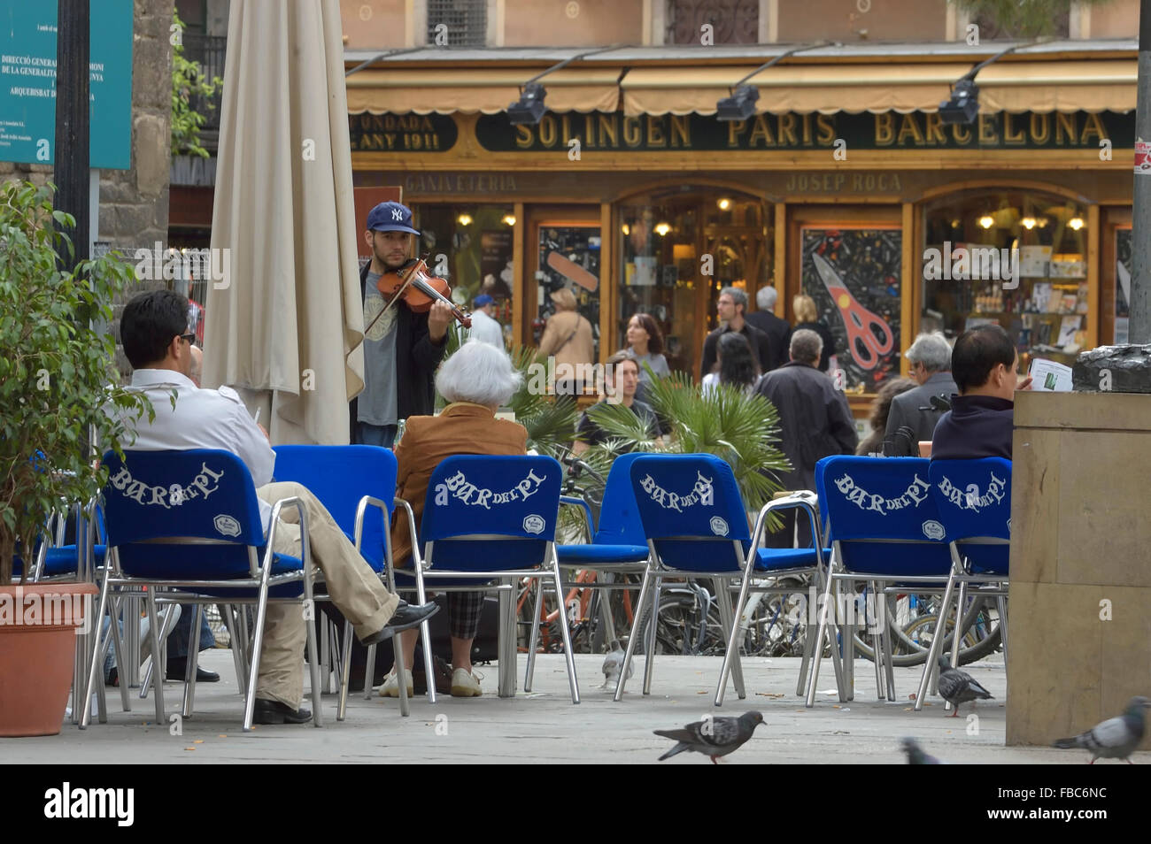 Busker playing to customers outside the bar del Pi. Barcelona. Catalan ...