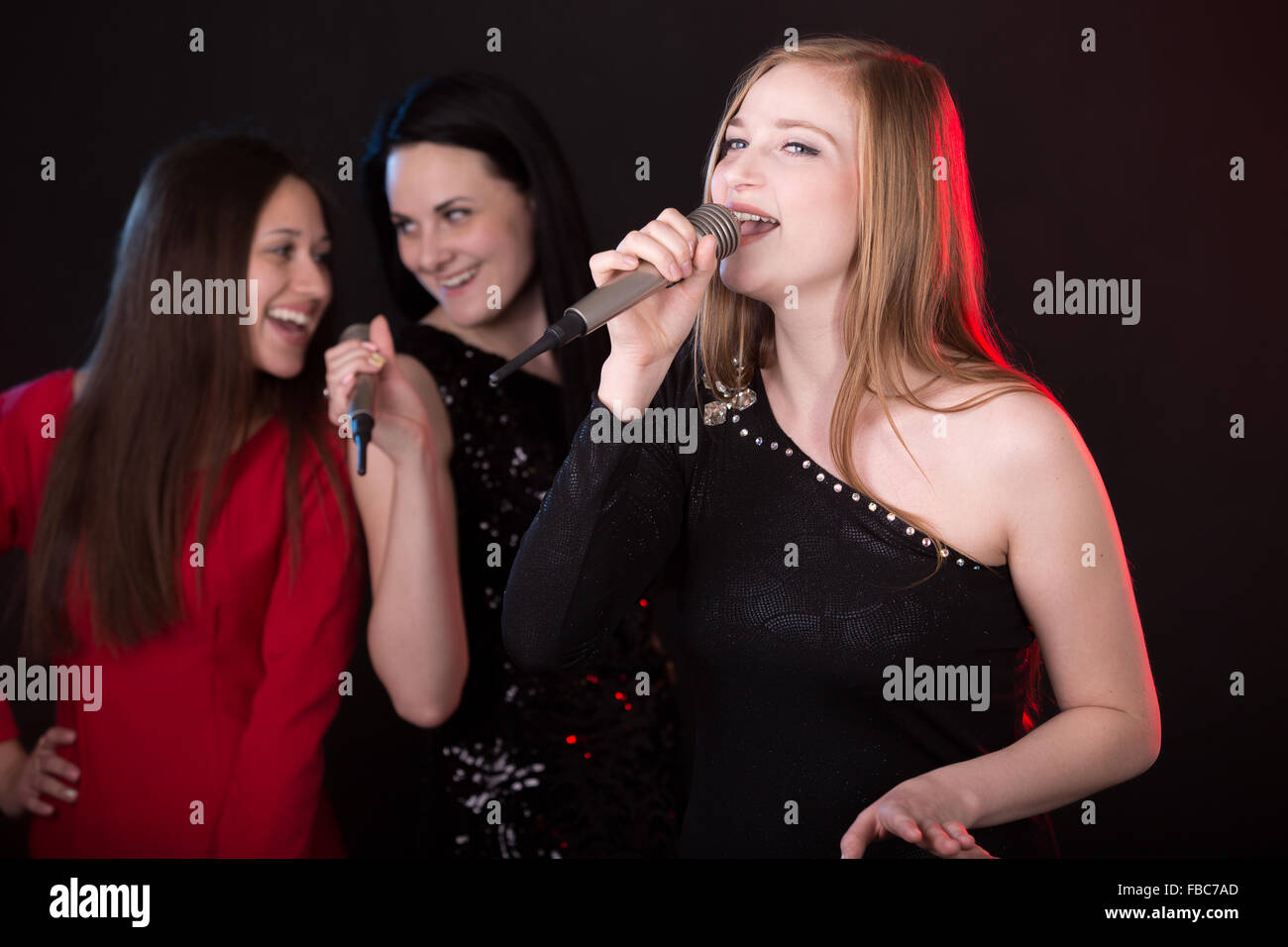 Portrait of beautiful emotional female singer with microphone singing ...