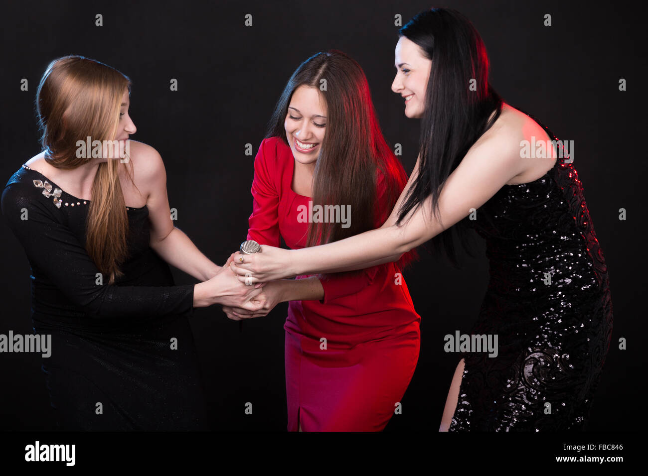 Group of friends having fun, fighting for microphone, black background ...