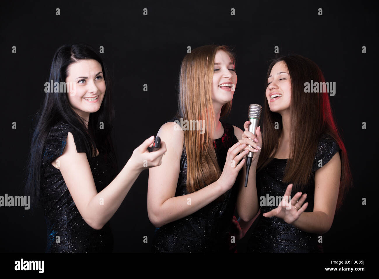 Three beautiful girls in karaoke, focus on brunette girl with remote ...