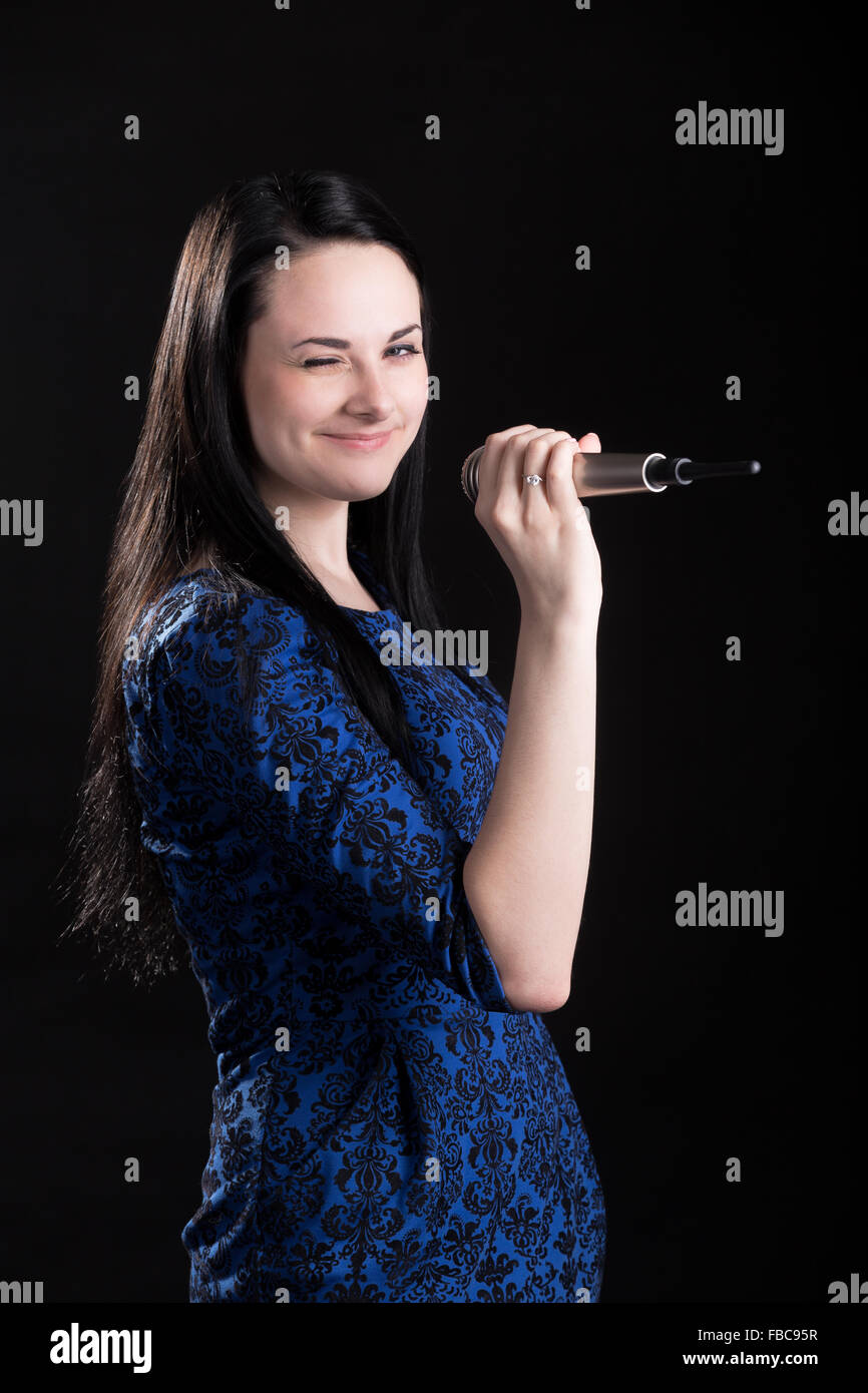 Portrait of smiling beautiful cute girl with microphone in blue dress ...