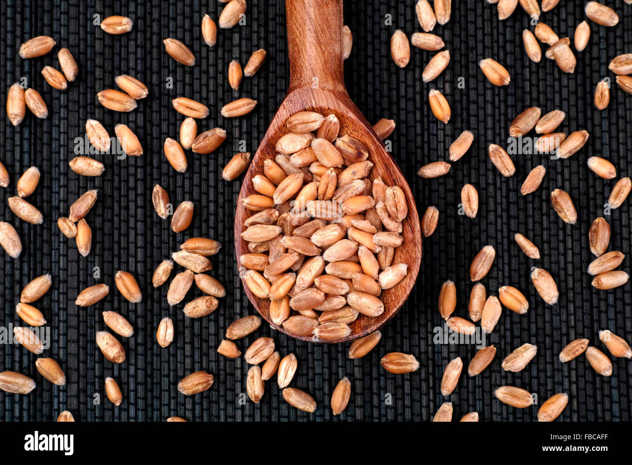 Organic whole wheat grain kernels in wooden spoon on black napkin Stock ...
