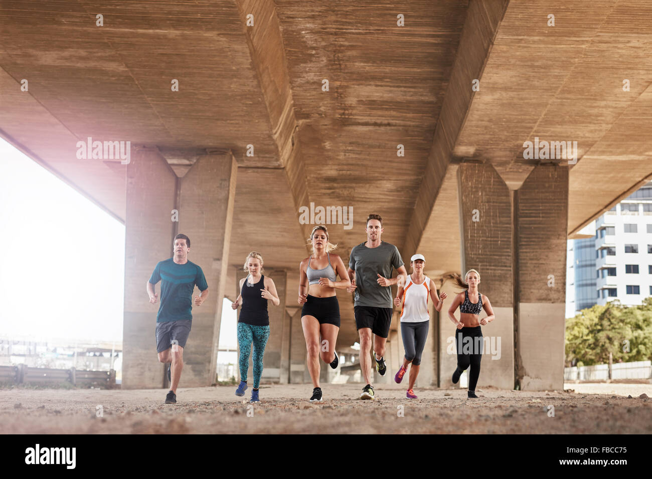 Group of healthy people running under a bridge. They are running in the ...