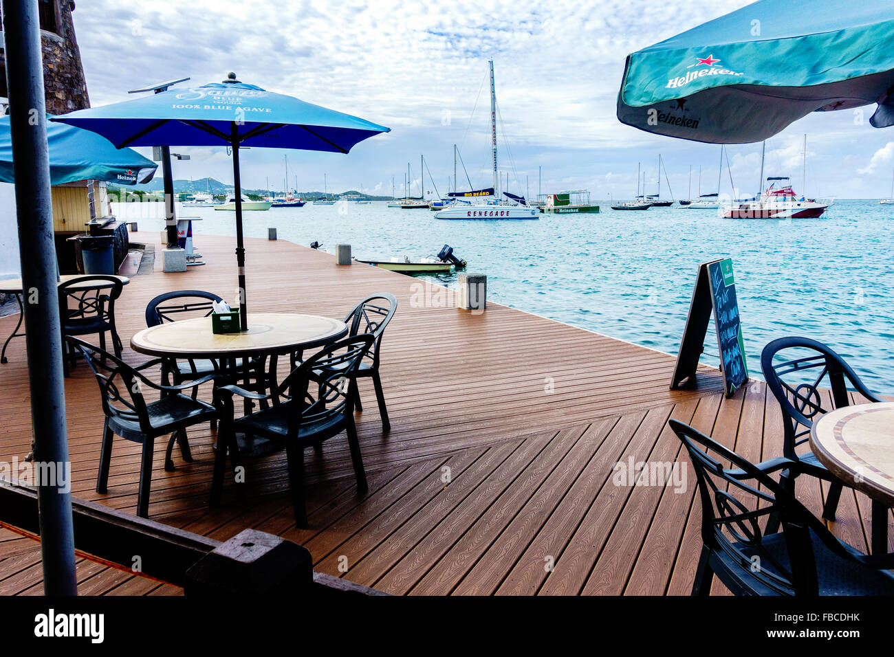 View of harbor and boats from beachside cafe with tables and chairs in ...