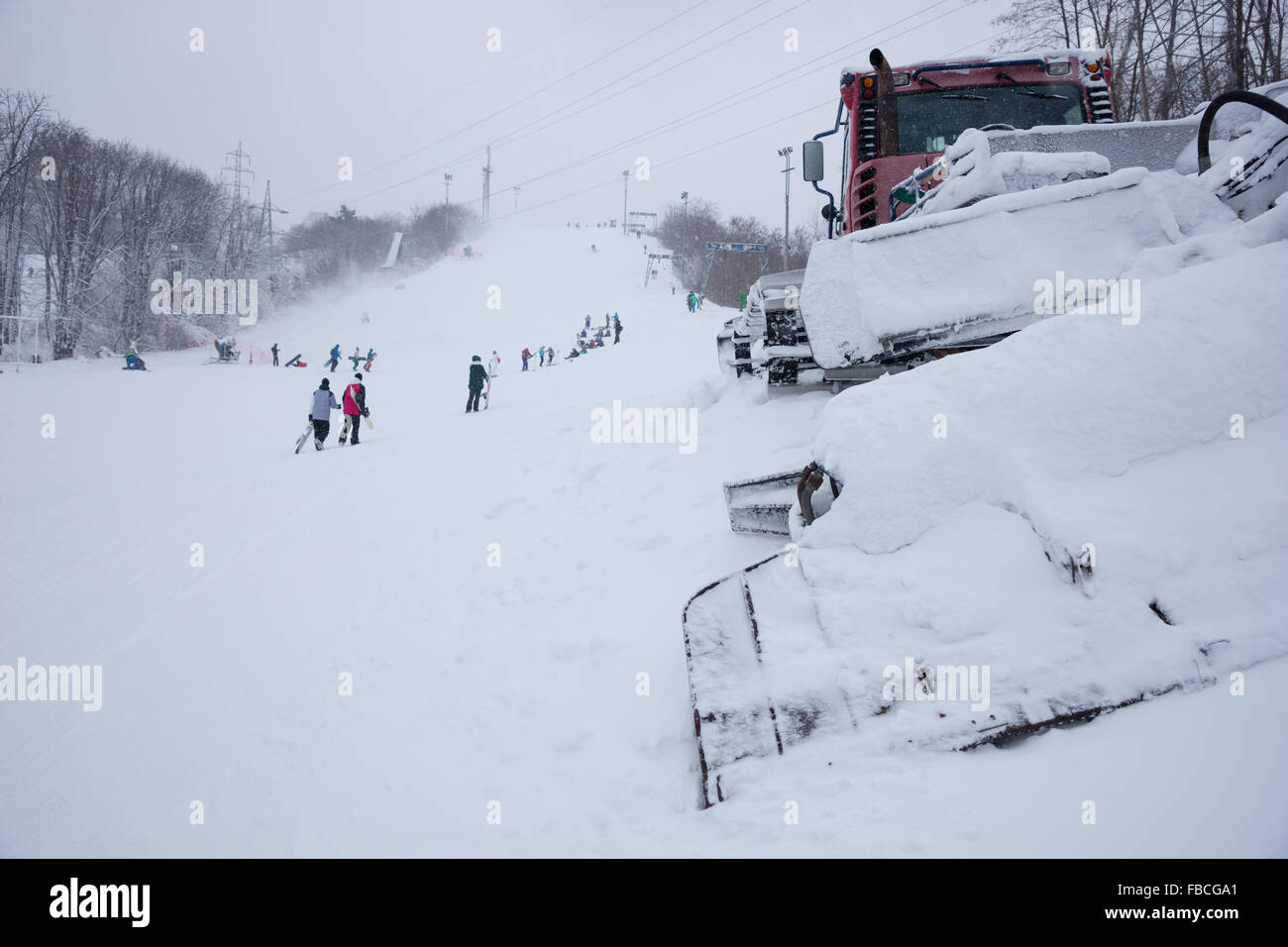 Snow plow alongside a ski run on a mountain resort with skiers on the ...