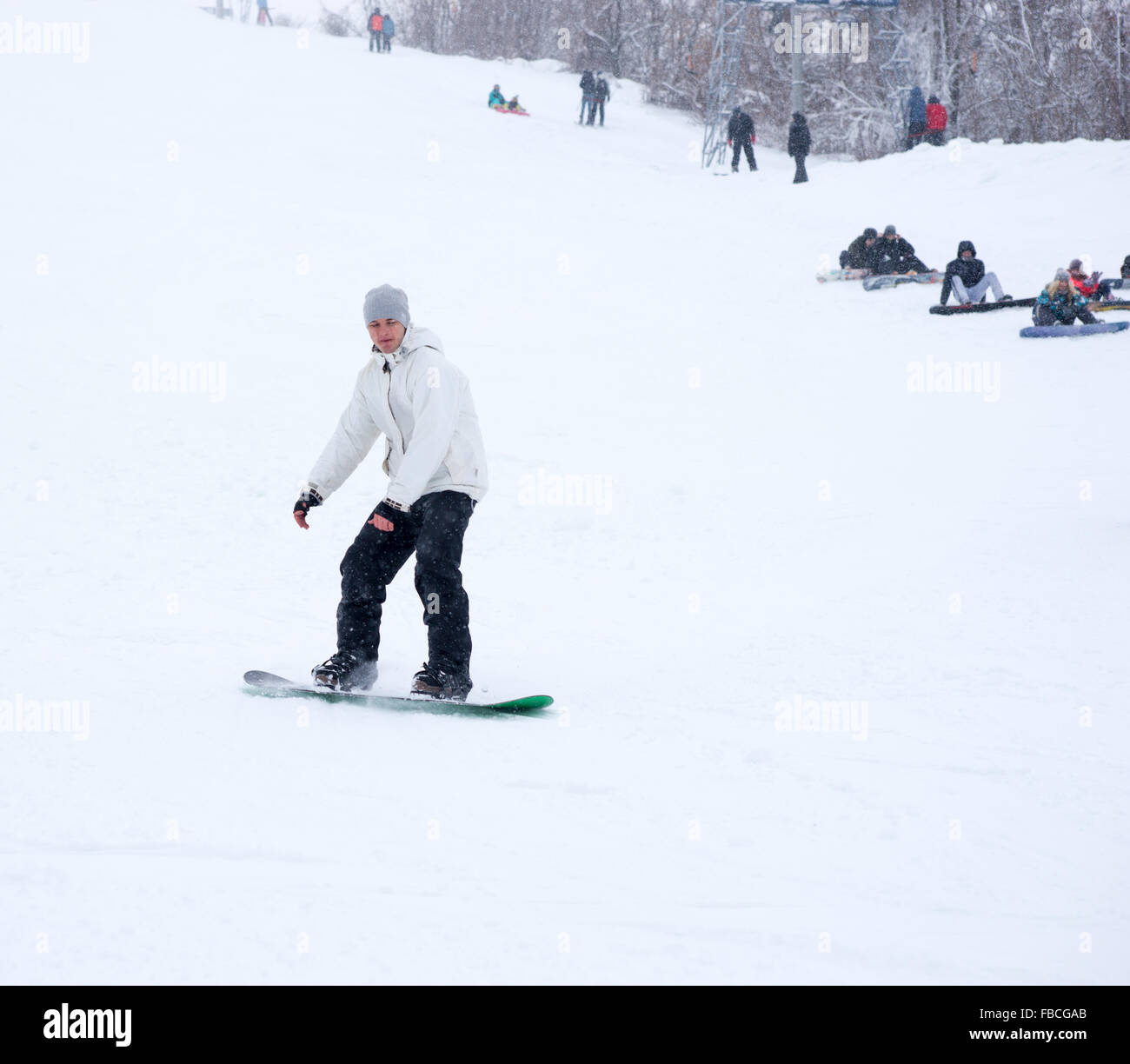 Young man snowboarding down a snow covered slope at a mountain ski ...