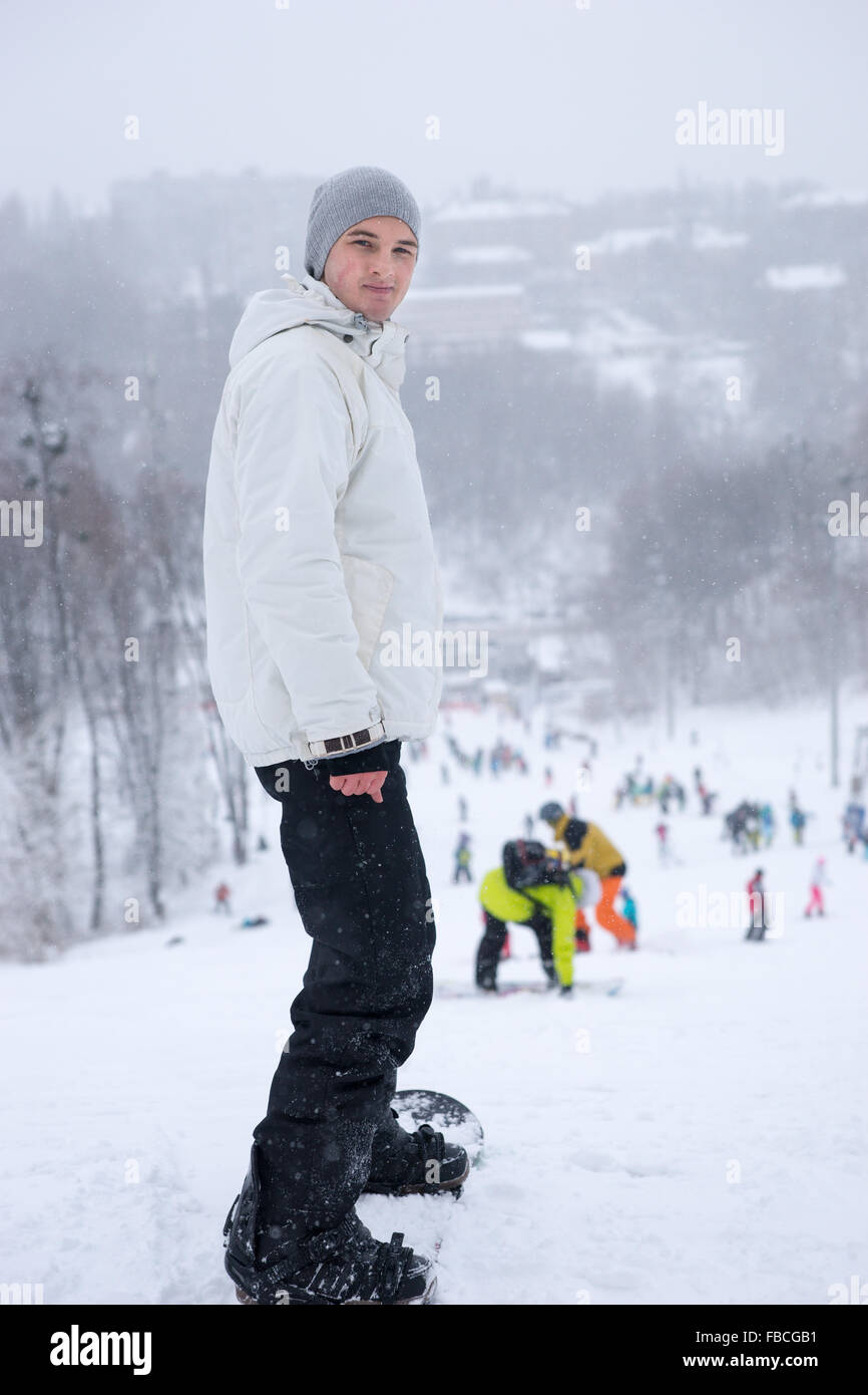 Attractive male snowboarder at the top of the run overlooking a winter ...