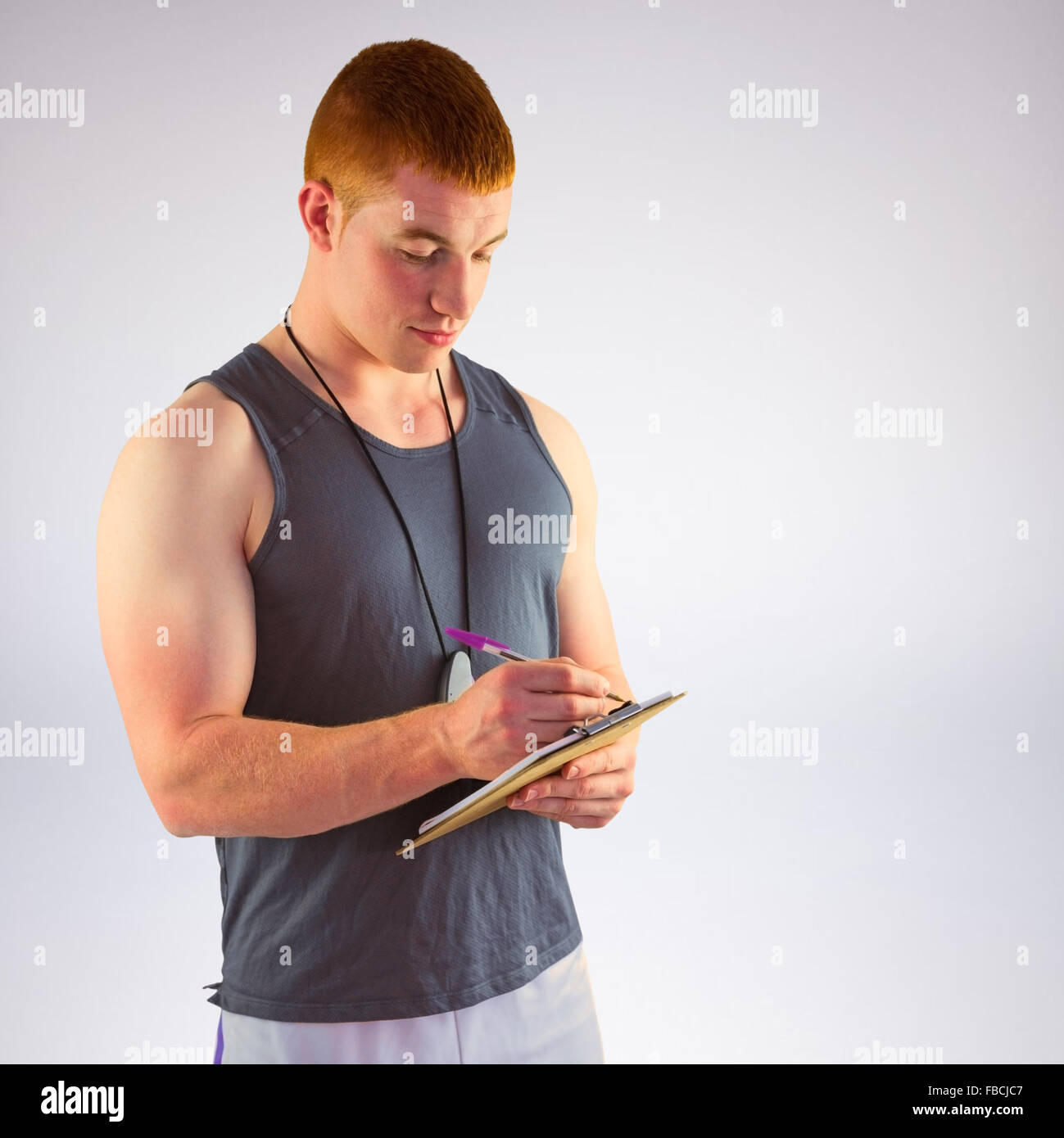Composite image of fit personal trainer writing on clipboard Stock ...