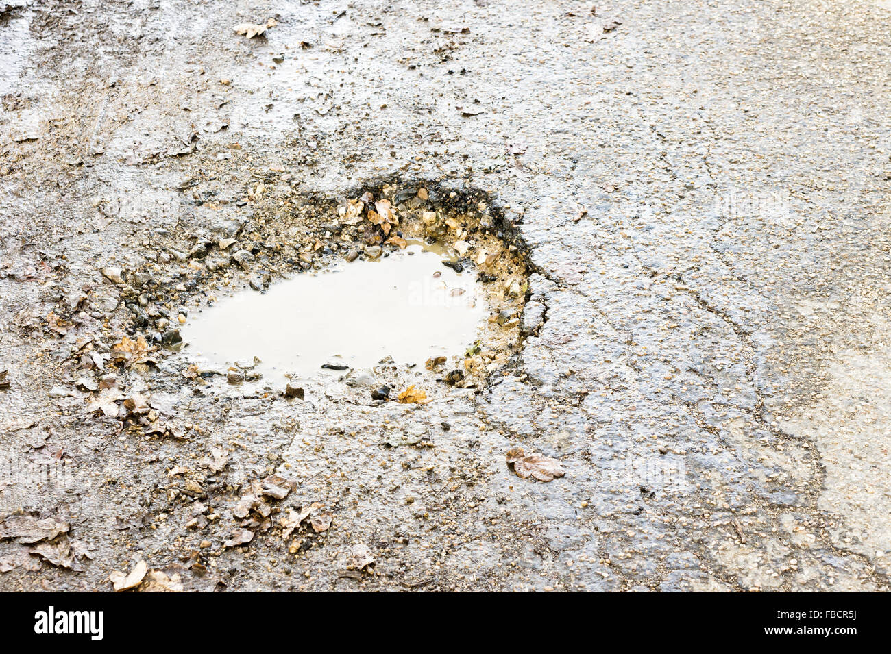 A pothole in a road surface with rainwater in it Stock Photo - Alamy