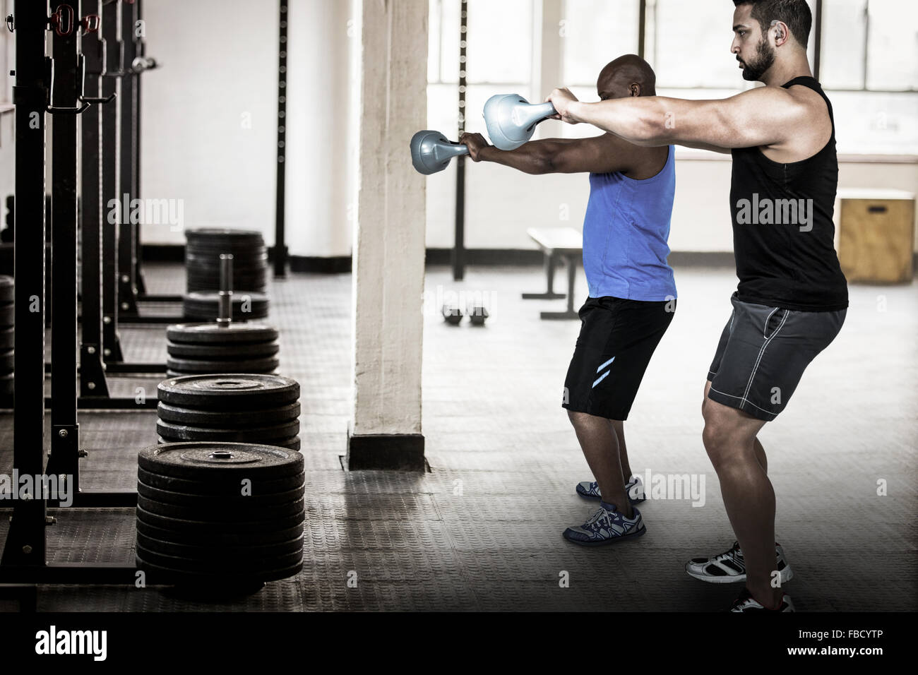 Composite image of strong friends lifting kettlebells together Stock ...