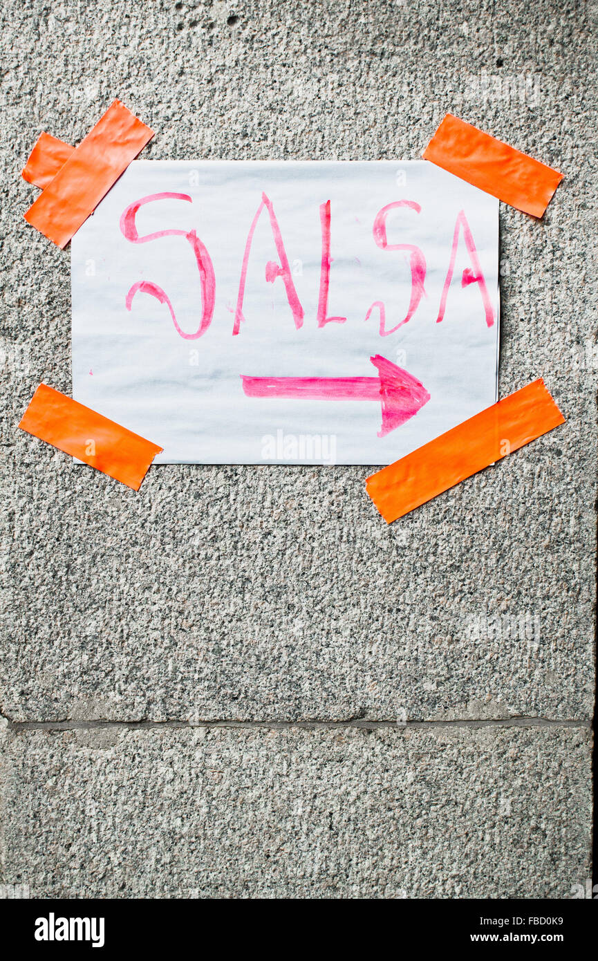 A sign for salsa on a white piece of paper stuck to a stone wall Stock ...