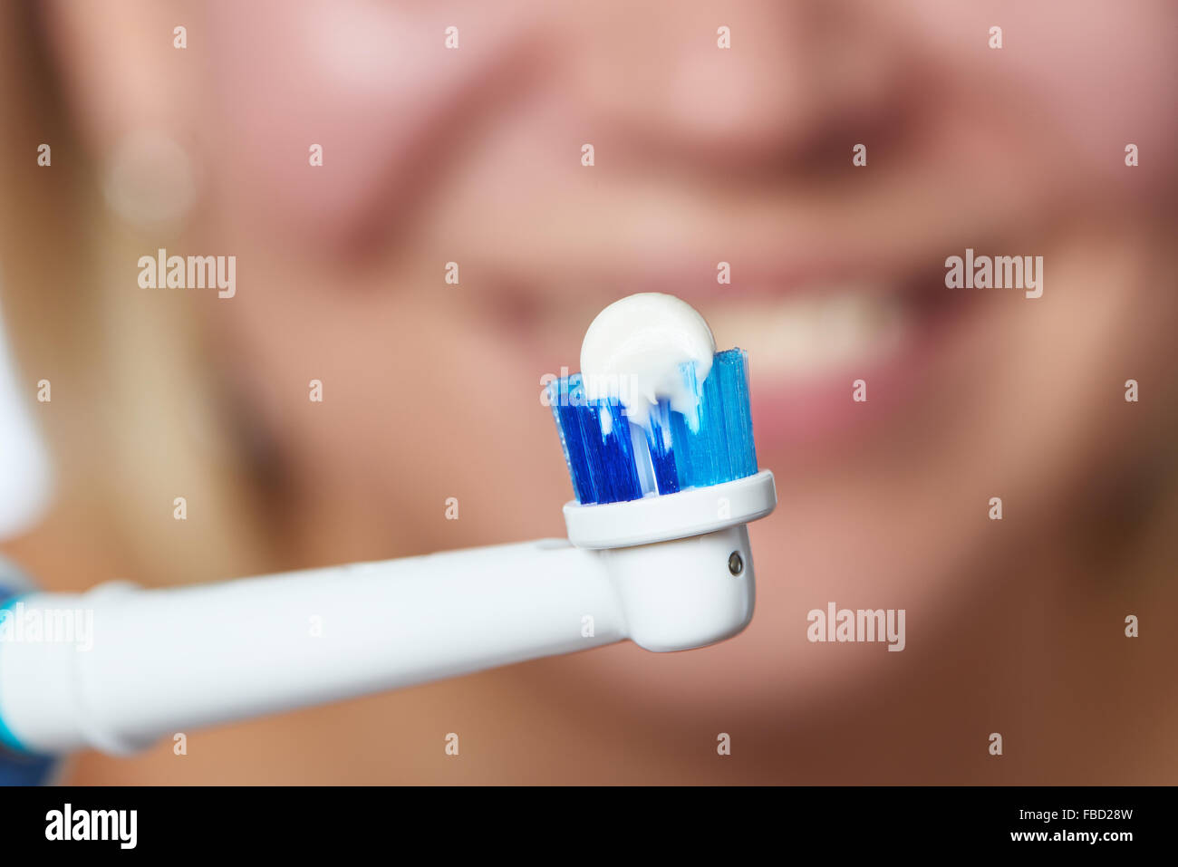 Woman brushing teeth electric toothbrush with toothpaste macro closeup ...