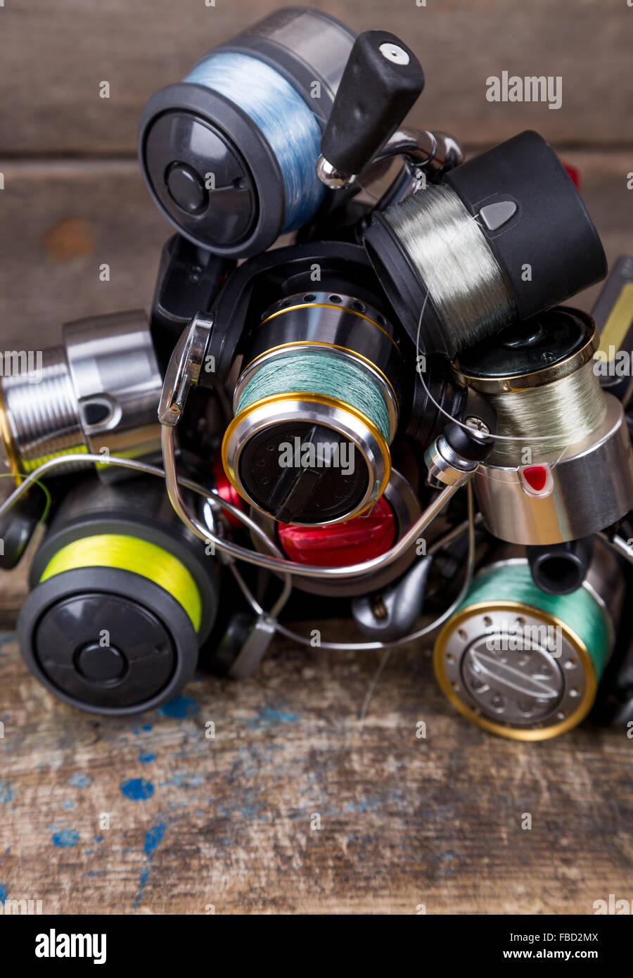 heap different fishing reels with line on wooden background. color ...