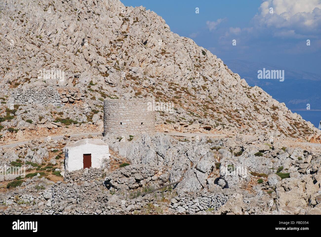 A small chapel and an old stone windmill in the rocky hills above ...