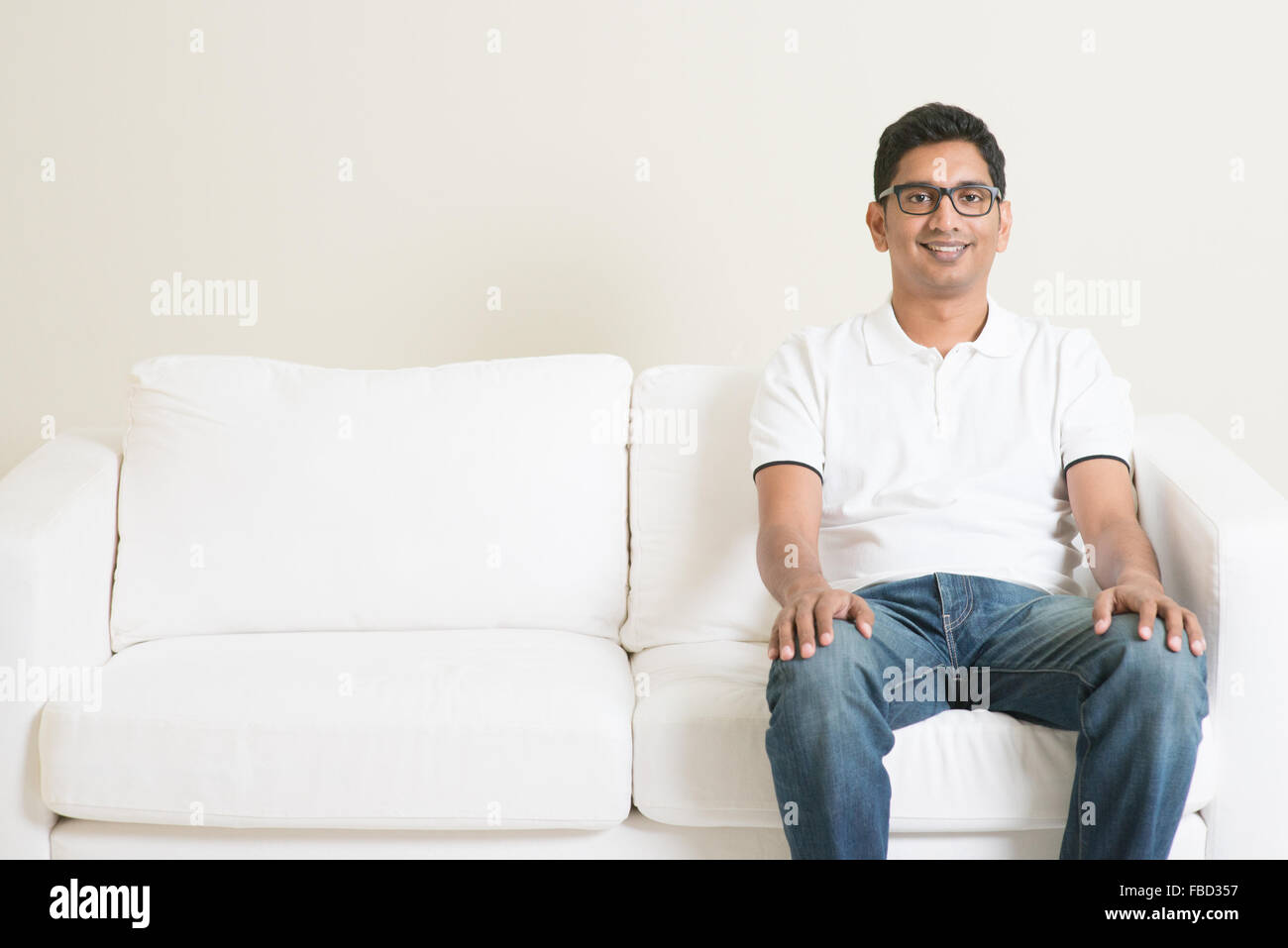 Young single Indian guy sitting lonely on sofa and smiling. Lifestyle ...