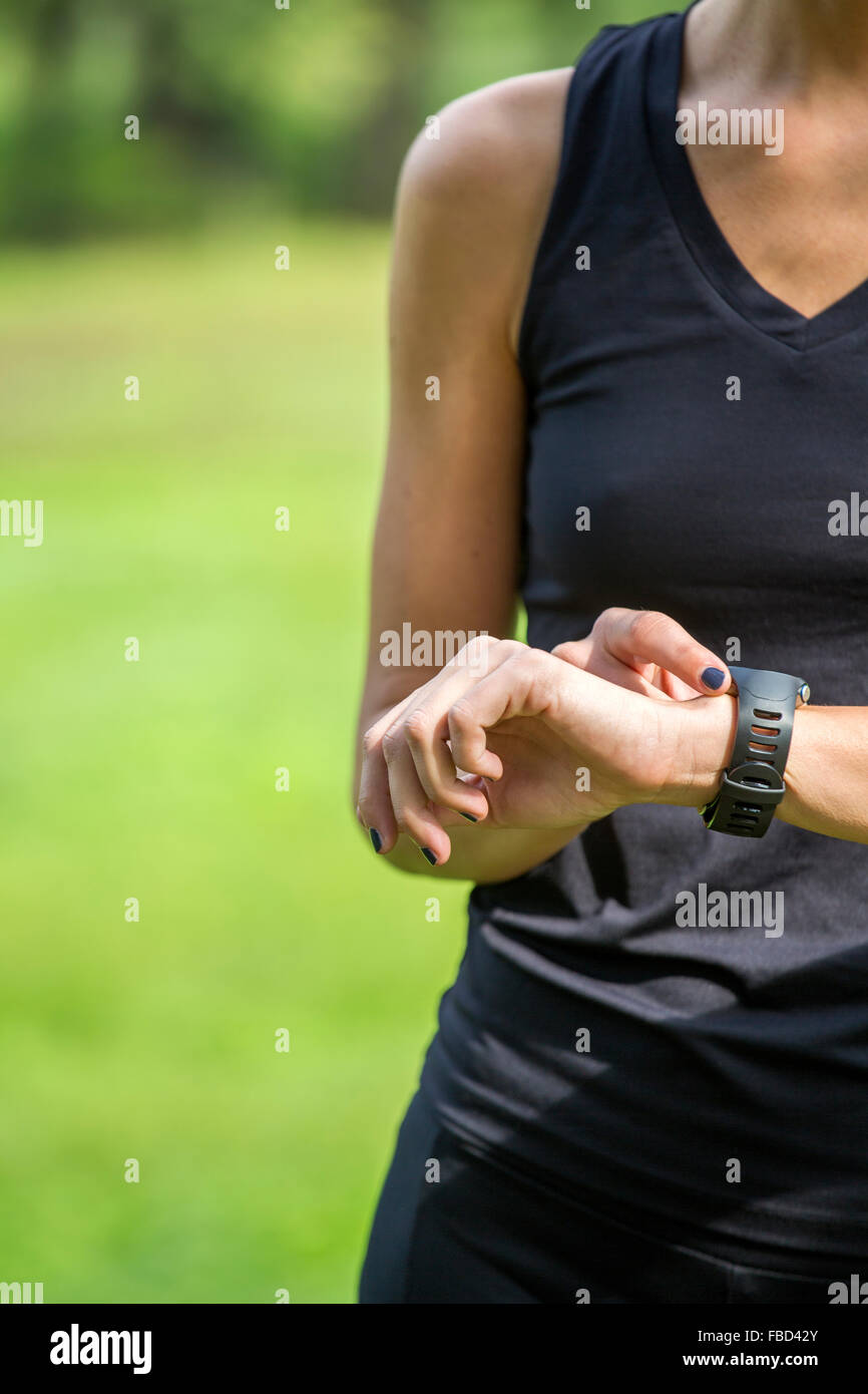 Young woman looking at watch during outdoors training Stock Photo - Alamy