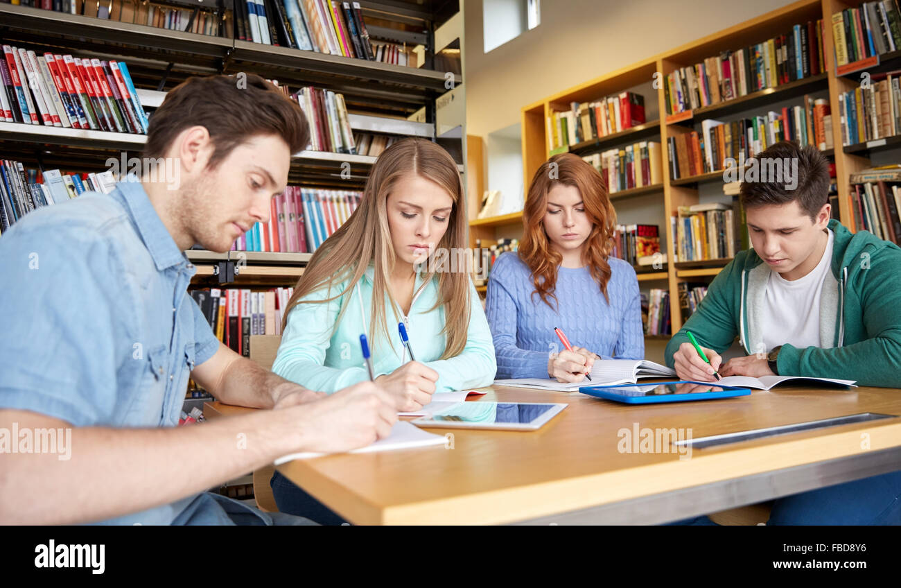happy students writing to notebooks in library Stock Photo - Alamy