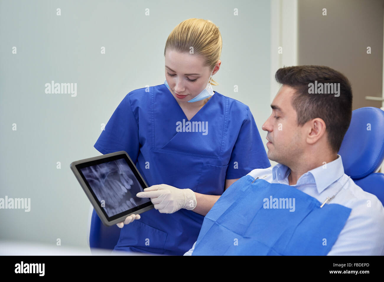 female dentist with tablet pc and male patient Stock Photo - Alamy