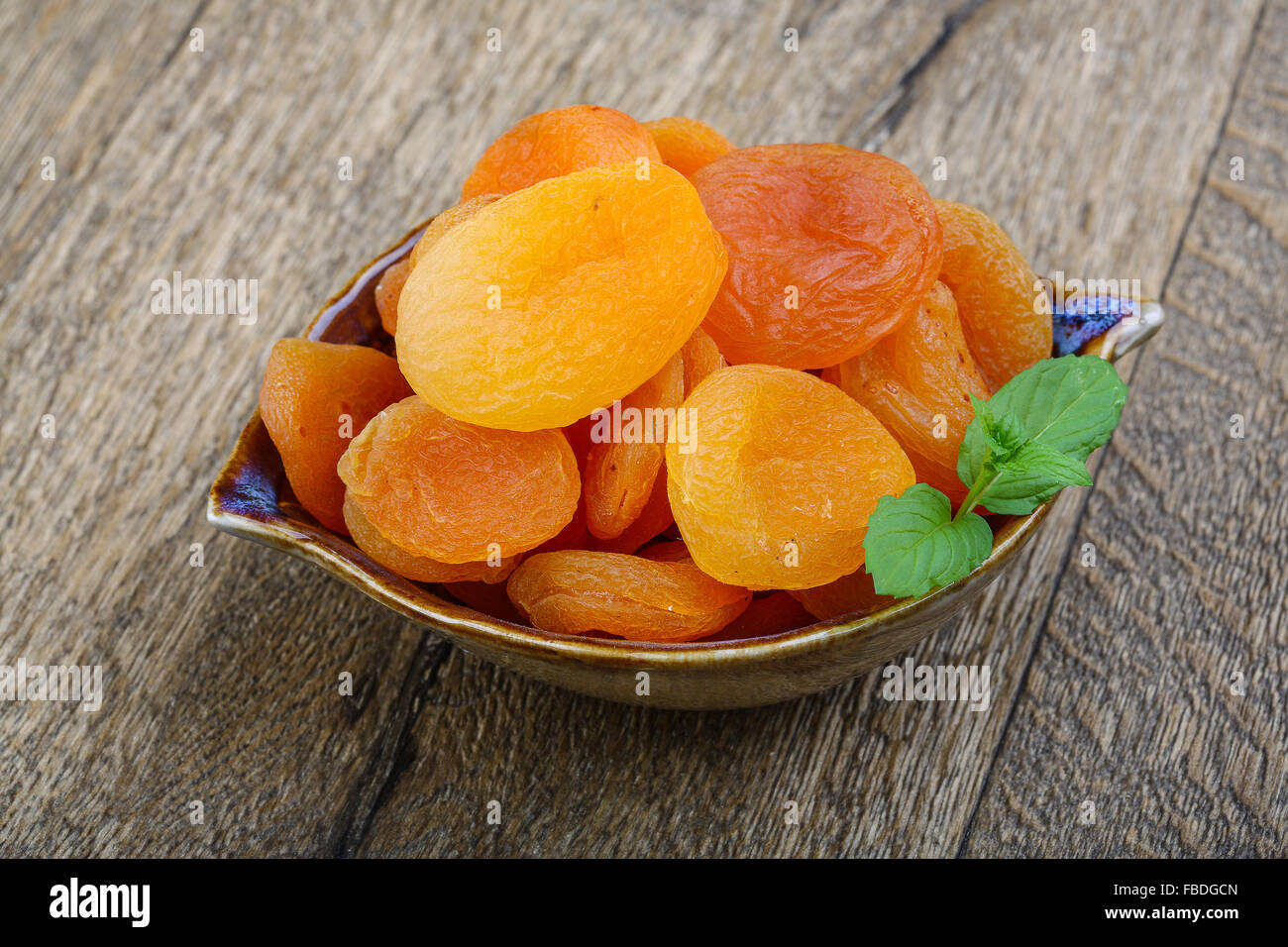 Dried apricots in the bowl on the wood background Stock Photo - Alamy