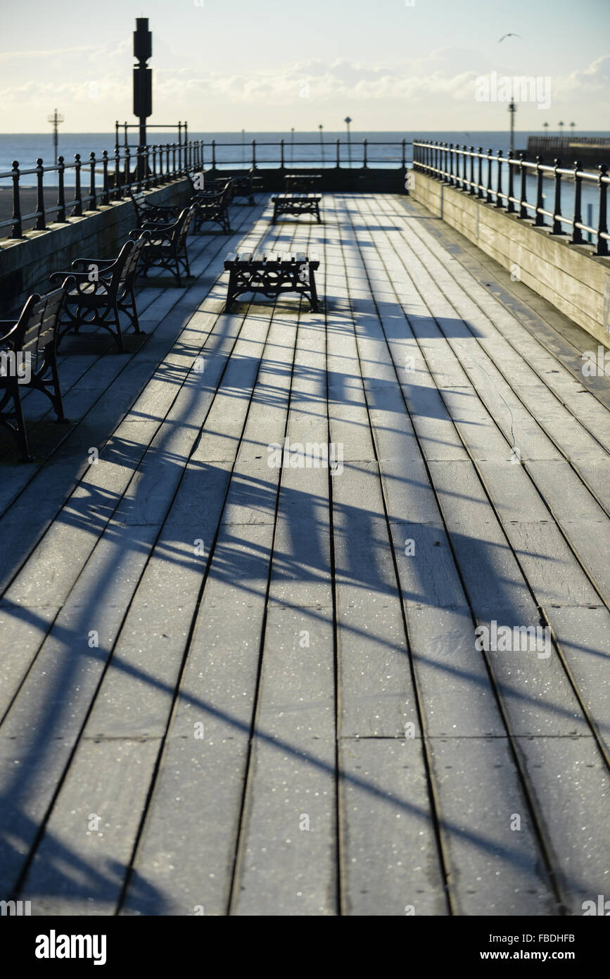 Long shadows are cast onto the frost covered wooden decking of ...