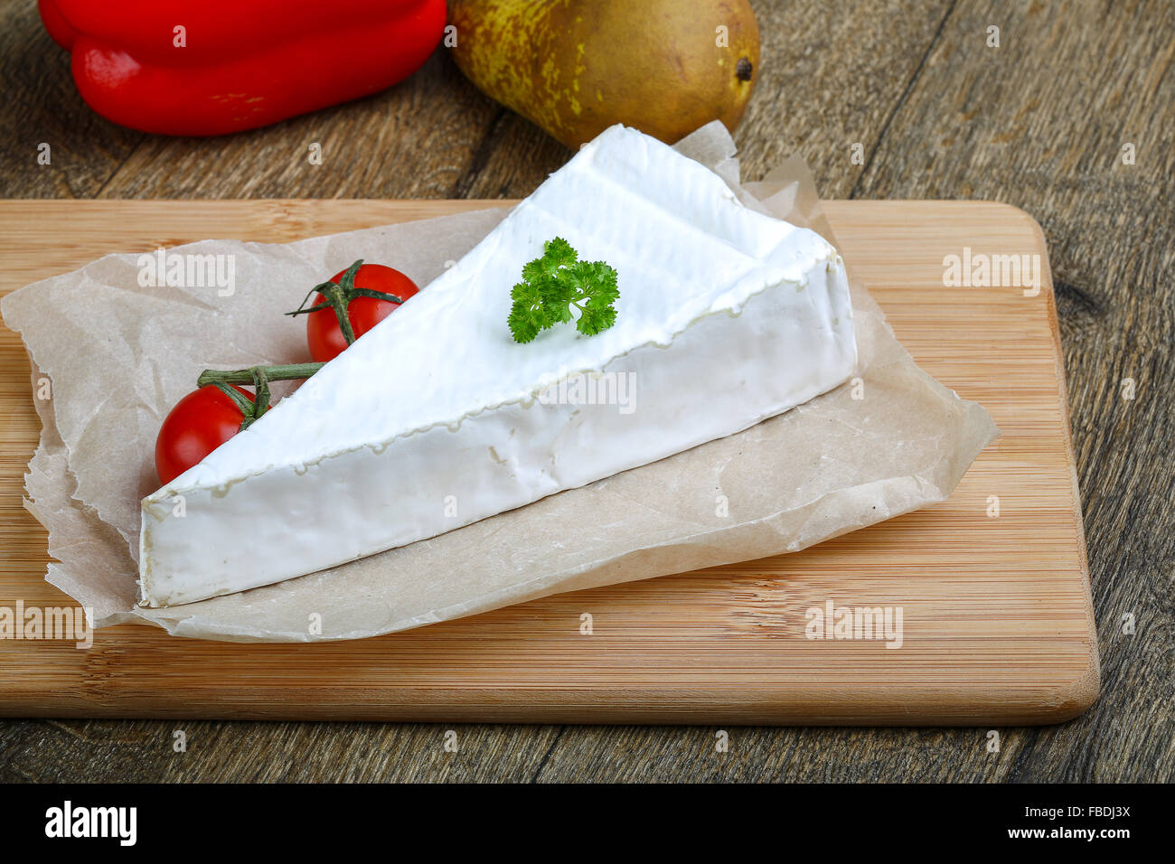 Brie cheese triangle with tomato and parsley Stock Photo - Alamy