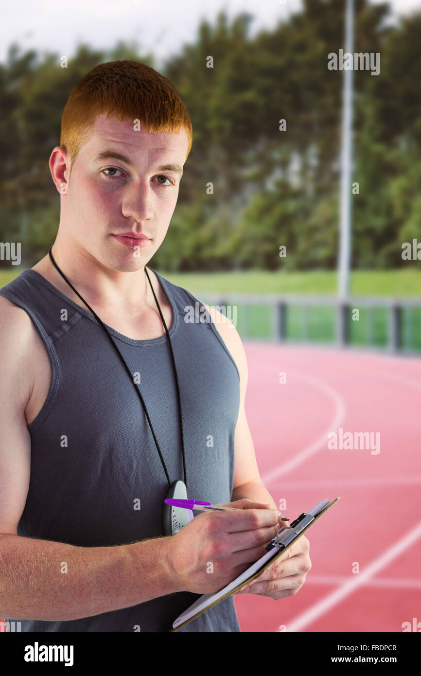 Composite image of fit personal trainer writing on clipboard Stock ...