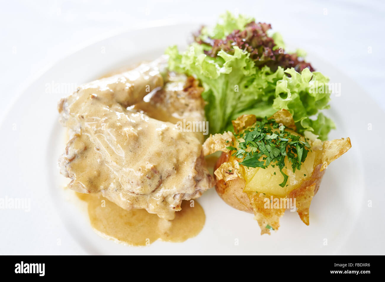 Rabbit in sauce with potato on white plate Stock Photo - Alamy