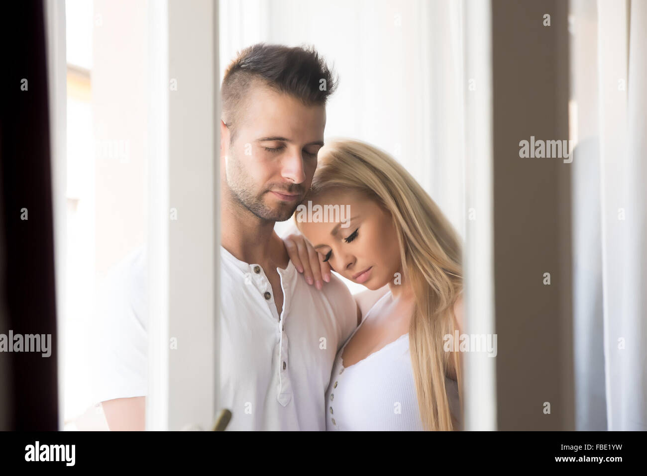 A beautiful young couple standing at the window at home Stock Photo - Alamy