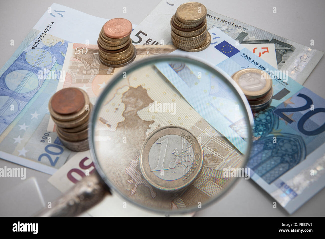 Money and magnifying glass Stock Photo - Alamy
